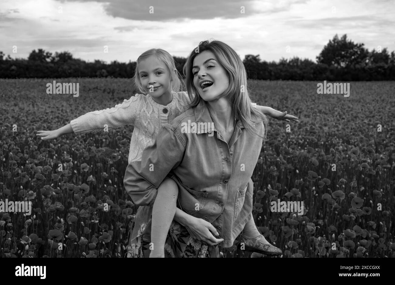 Mother and daughter walking through a flowering poppy field. Child and ...