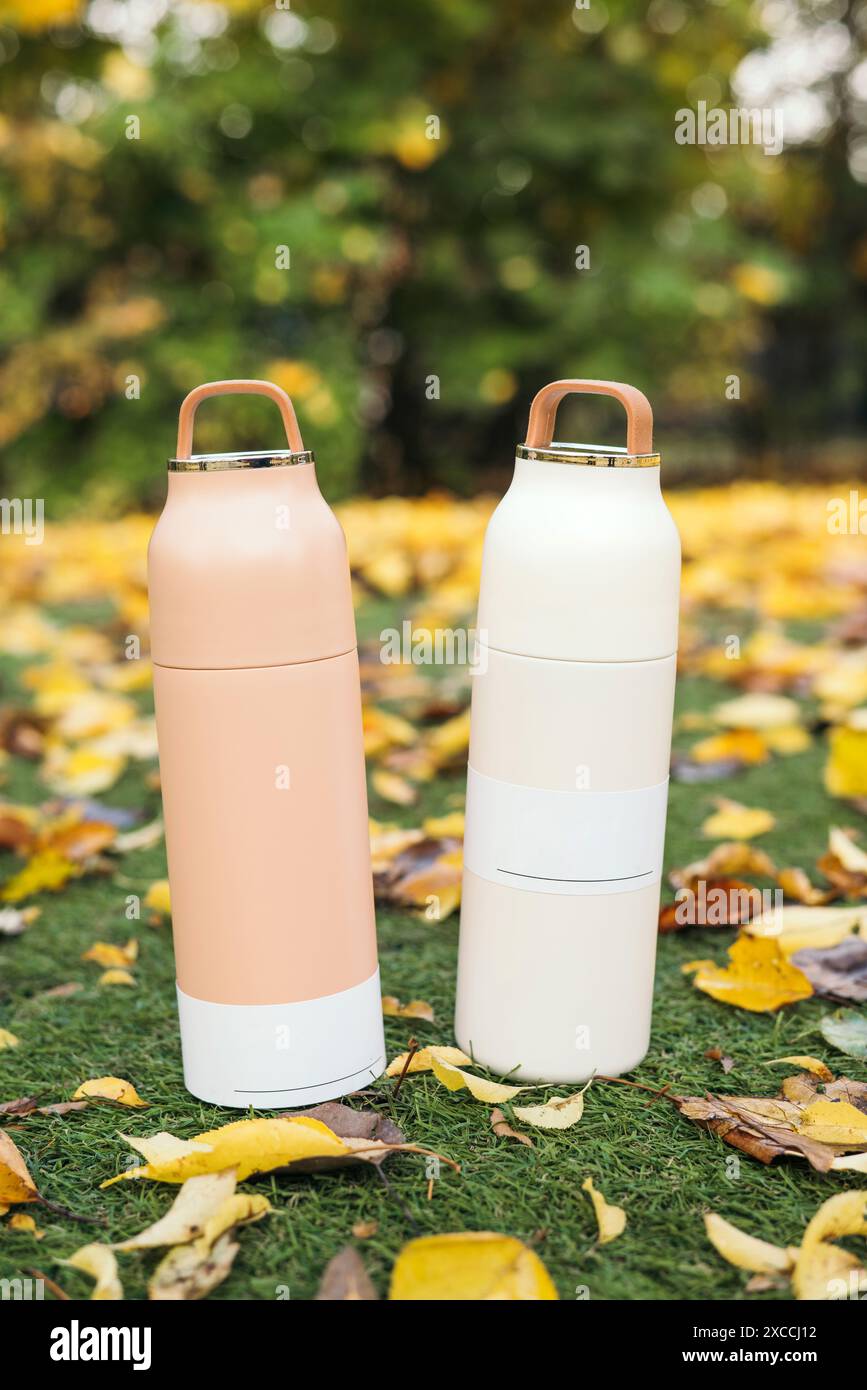 Modern stainless steel and plastic thermos with cup on park in autumn ...