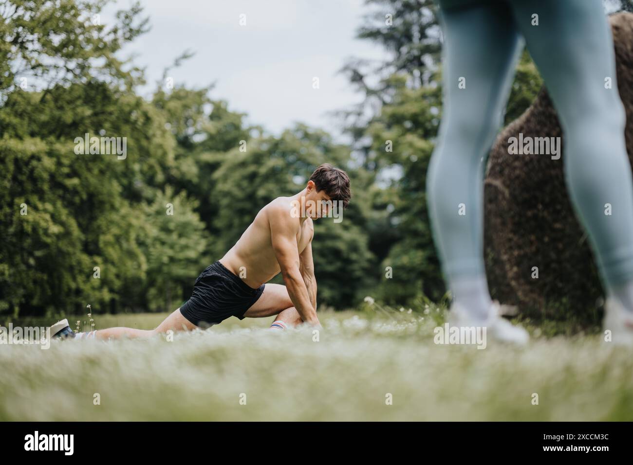 Man performing a warm-up stretch exercise in outdoor park setting Stock ...