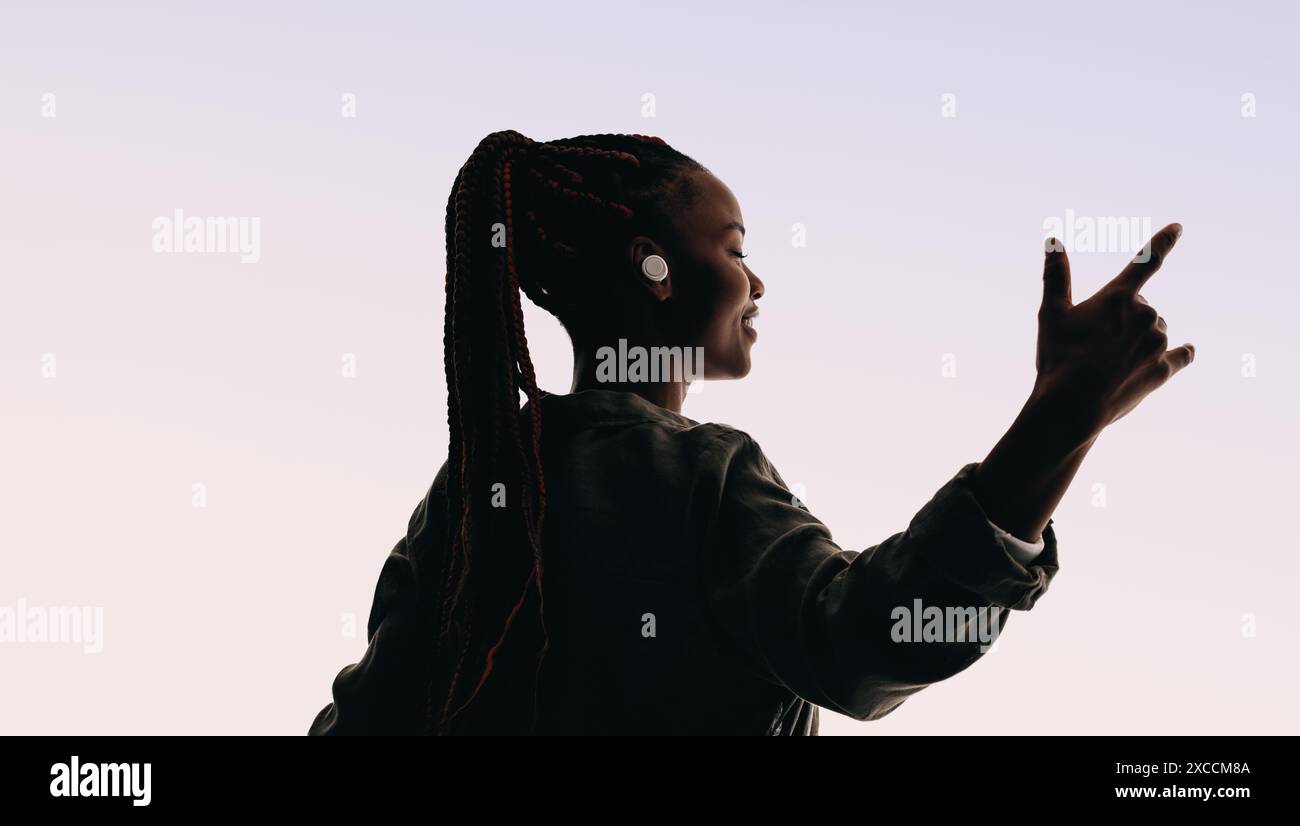 Carefree young woman with braids dances in a studio, expressing joy and ...