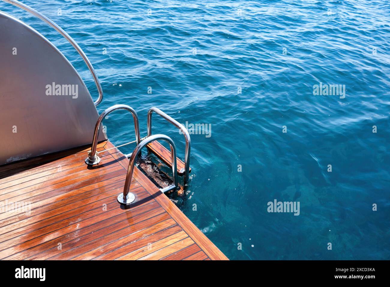 Back teak wooden deck and metal ladder of a of motor yacht over the sea ...