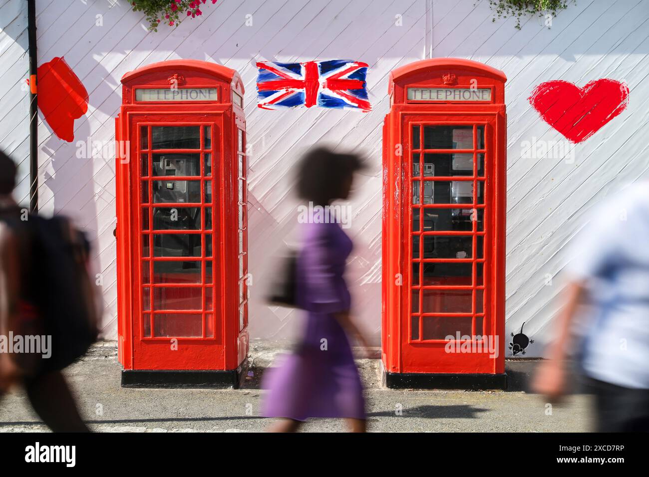 Classic red British telephone booths with blurred pedestrians in motion ...