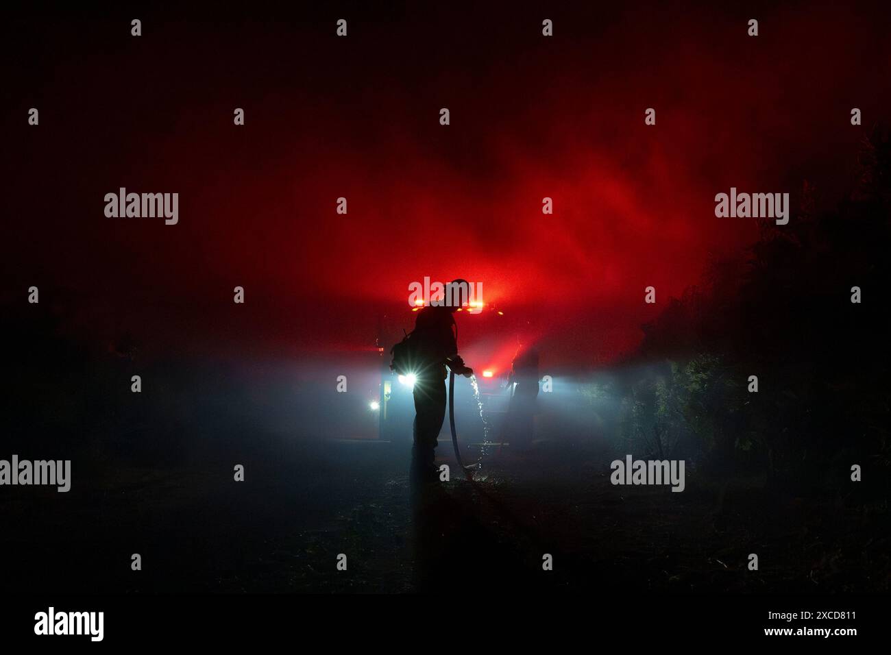 A Cal Firefighter prepares a water hose to put out brush fires. The ...