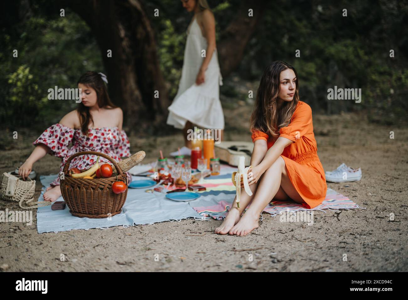 Young women enjoying a summer picnic in the forest with fresh fruits ...