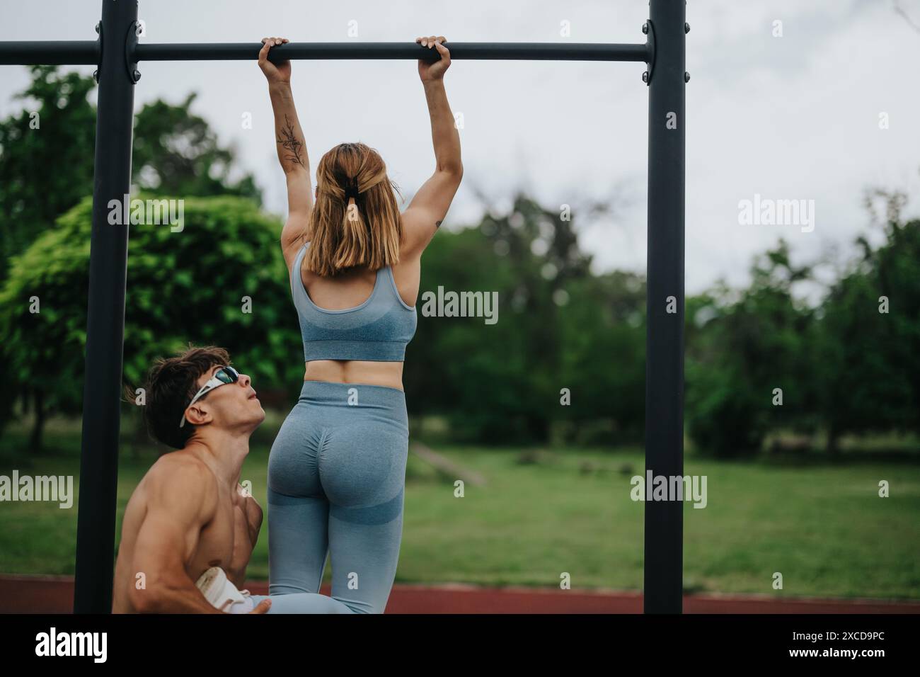 Fitness enthusiasts performing pull ups outdoors to exercise biceps ...