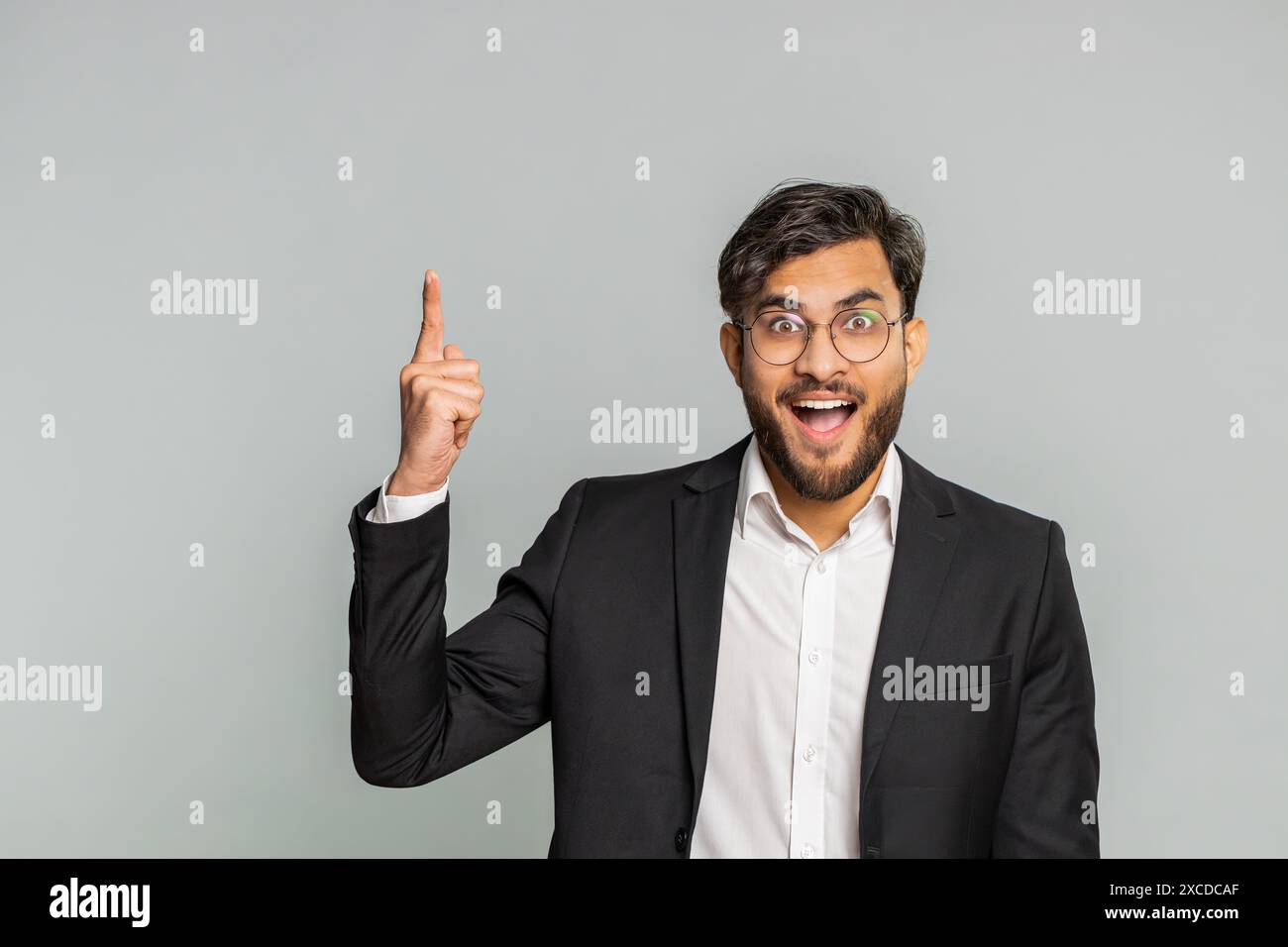 Eureka. Inspired Indian businessman pointing finger up with open mouth ...