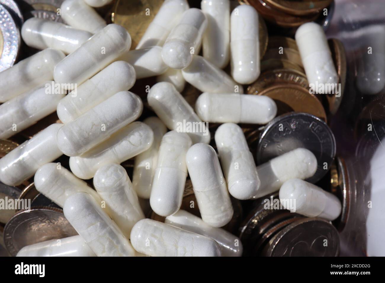 White and red capsules pill spilled out over several coins Stock Photo ...