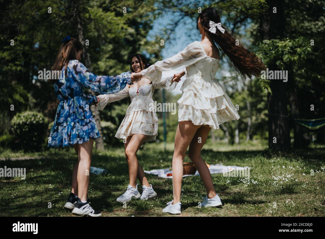Joyful sisters dancing in a circle in a sunny park, celebrating ...
