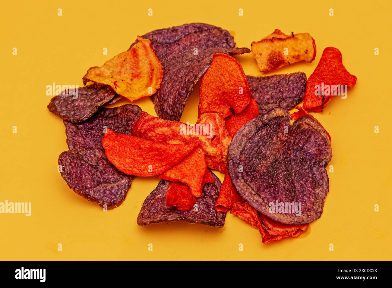 Colorful baked vegetable crisps pile snack on yellow background Stock ...