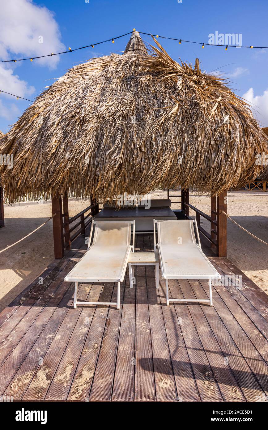 Close-up view of a palm leaf-covered cabana on the sandy beach of a ...