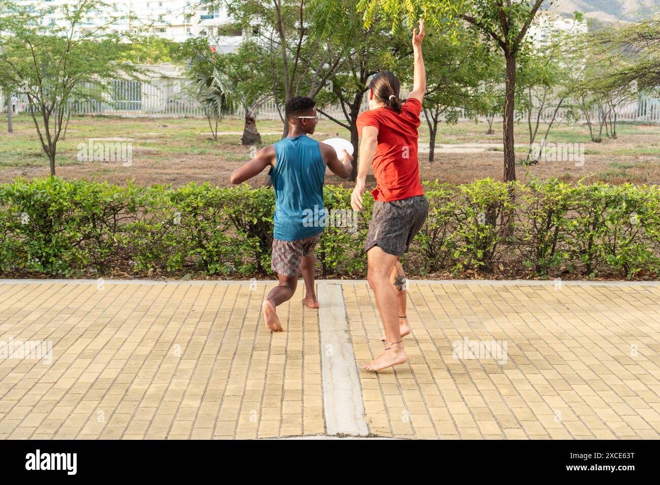 Two men engaged in an exciting frisbee game on a paved outdoor court ...