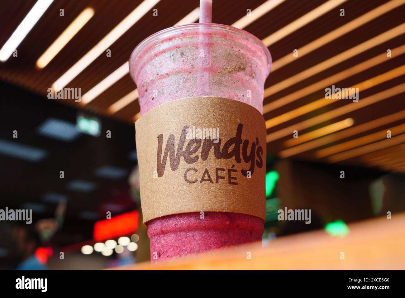 A half-empty cup of pink beverage sits on a table in a Wendy's restaurant, shot from a low angle ...