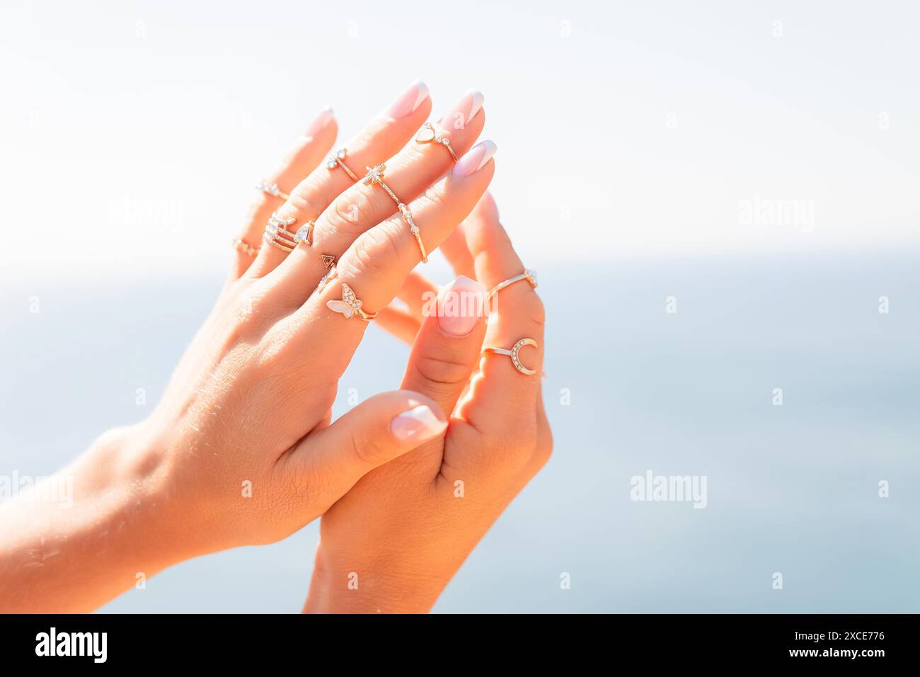 A woman is holding her hands up with a variety of rings on her fingers ...