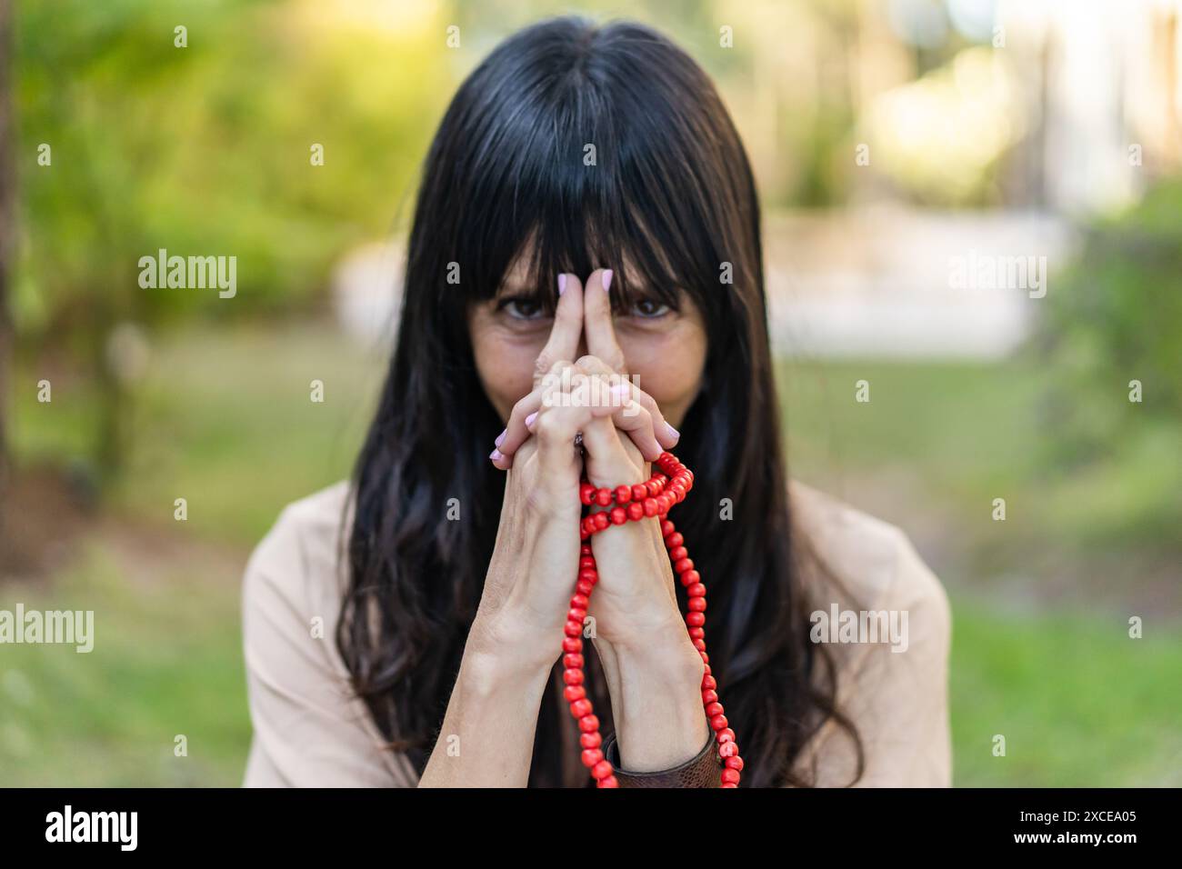 Woman holding a japa mala outdoors while looking at camera Stock Photo ...