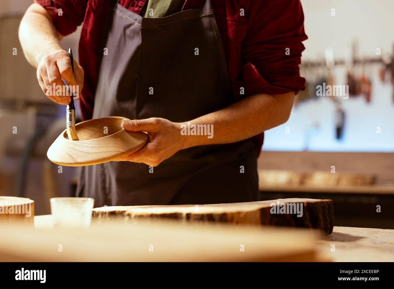 Artisan applying varnish on wood object to build up protective layer ...