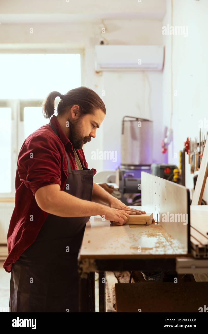 CNC machinist operating wood shaper in assembly shop, creating ...
