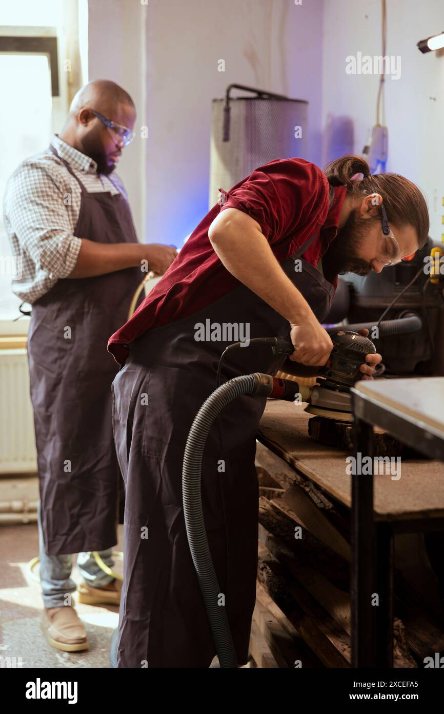 Carpenter and african american coworker using angle grinder on lumber ...