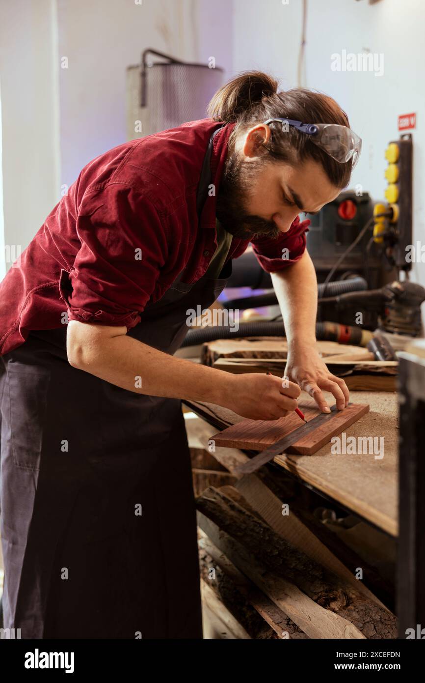 Carpenter using ruler to take measurements of wood plank used for ...