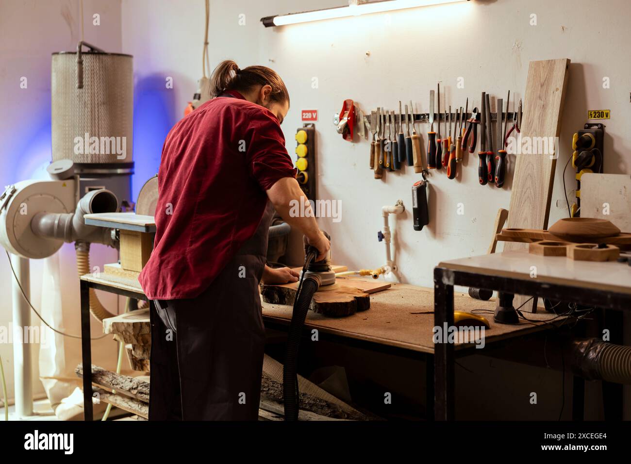 Artisan in studio using orbital sander with fine sandpaper on lumber to ...