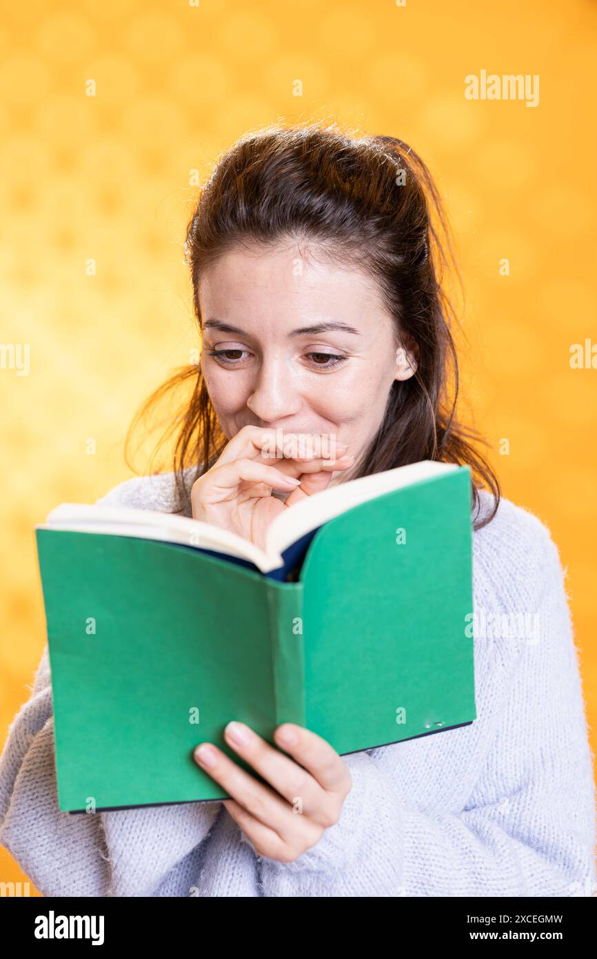 Amused woman browsing through funny book pages, laughing, having fun ...