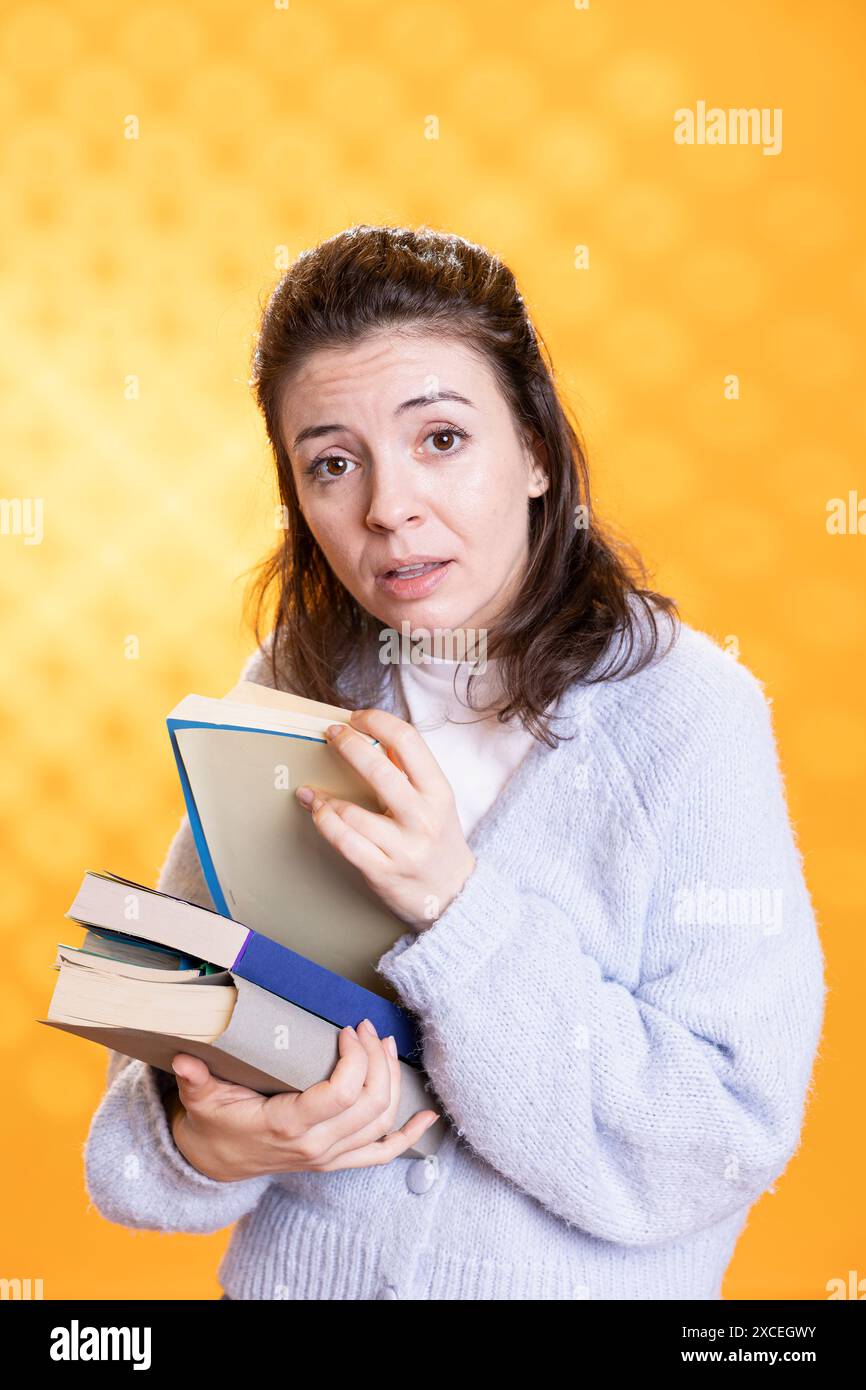Portrait of woman searching through stack of books in frenzy to gather ...