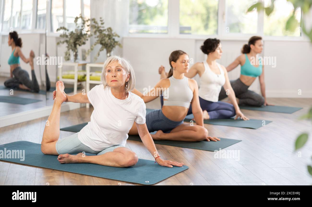 Group of women practicing yoga, working out doing version of Eka Pada ...