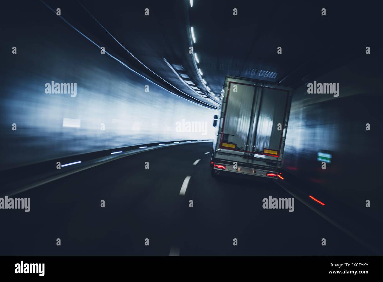 A large semi-truck travels through a dark, concrete tunnel. Motion ...