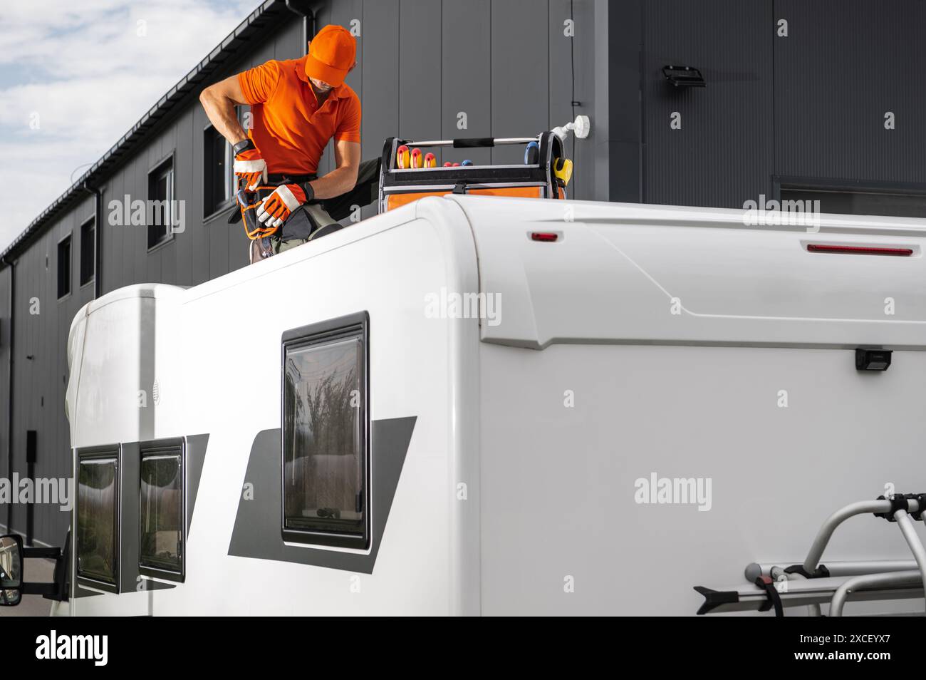 RV industry worker wearing an orange shirt and safety gloves is seen on ...
