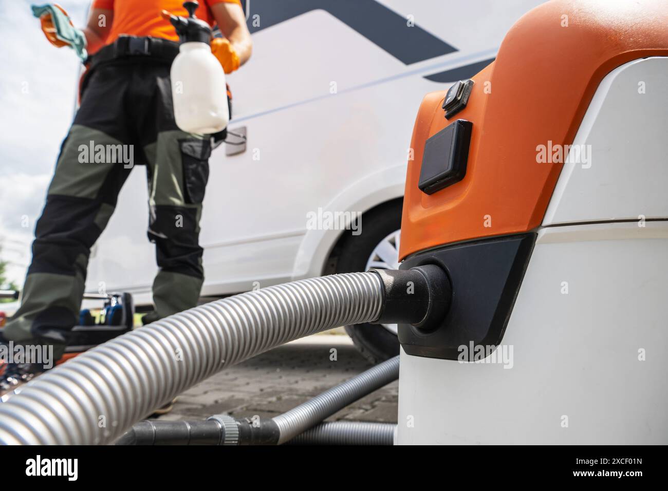 A worker cleans a white motorhome using a large industrial vacuum ...