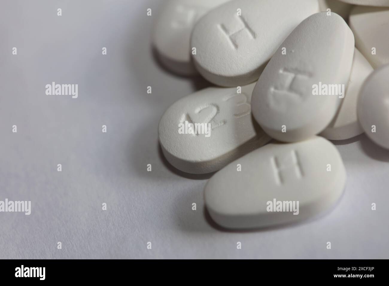 White pharmaceutical pills with numbers 123 and later h on back side ...