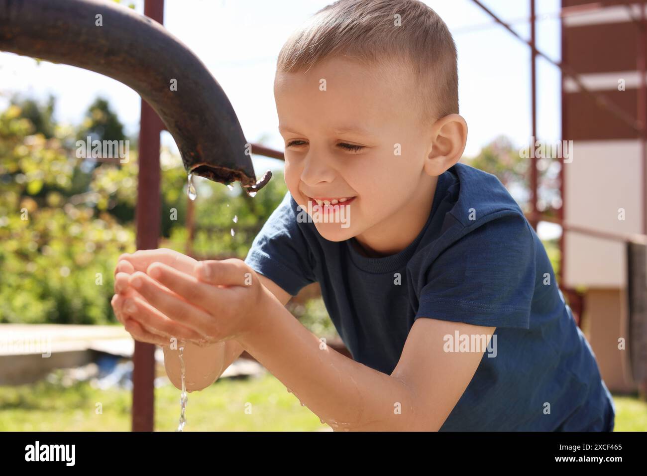 Water scarcity. Cute little boy drawing water with hands from tap ...
