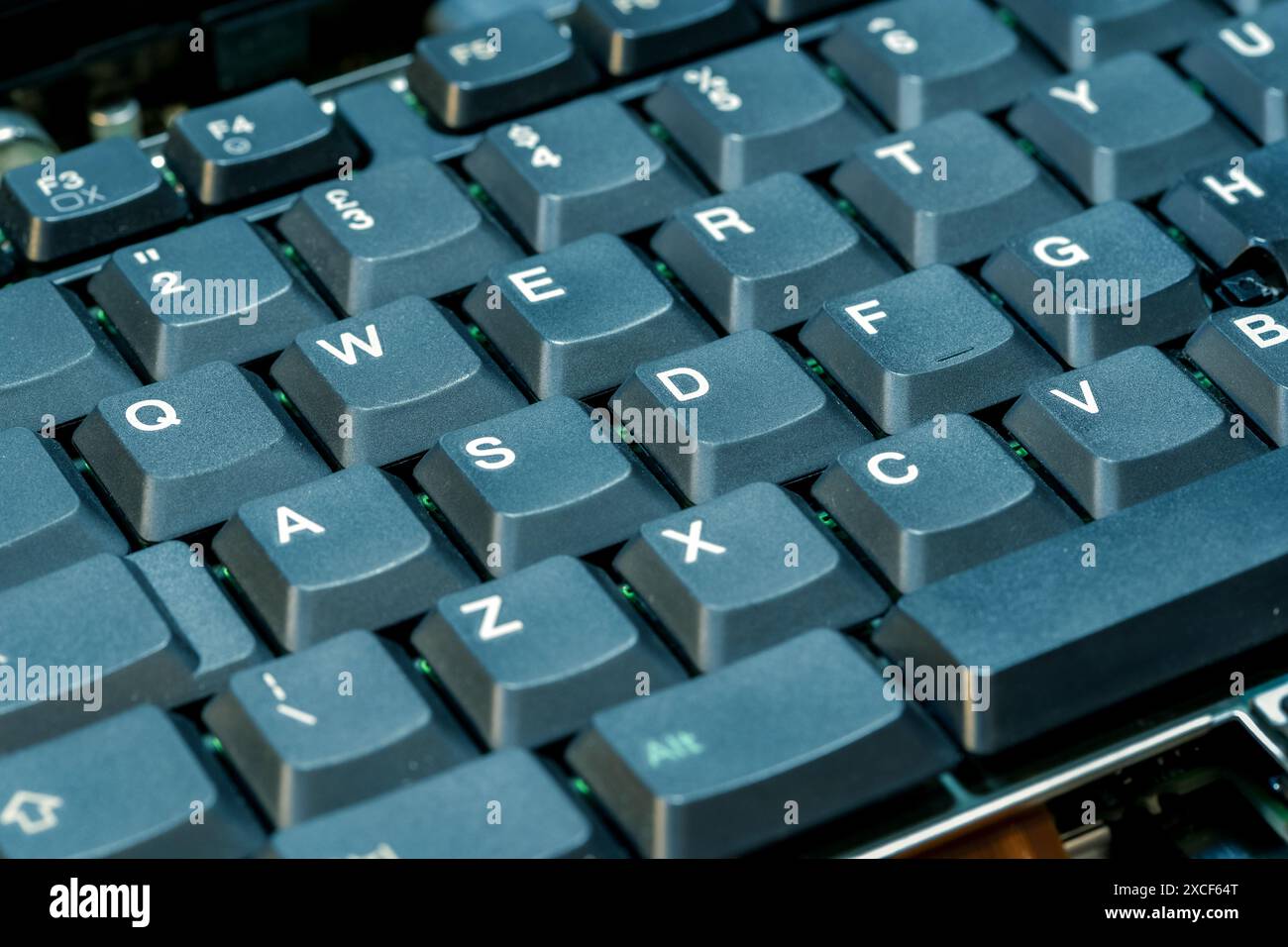 Old thick keys on a retro laptop computer keyboard soft blue green tint ...