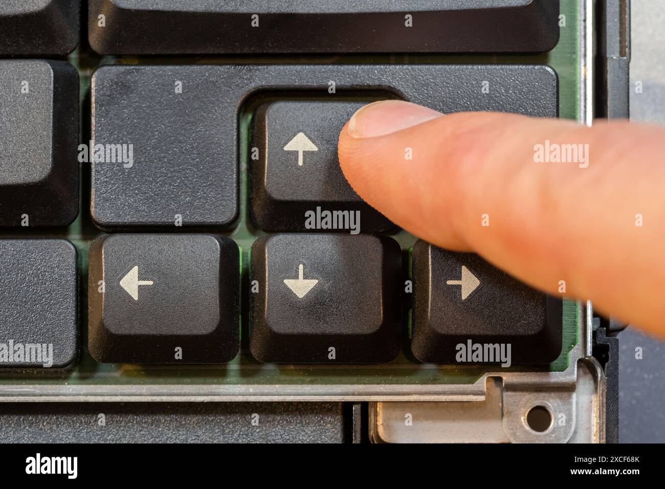 Man pressing the up arrow key on a simple laptop computer keyboard, top ...
