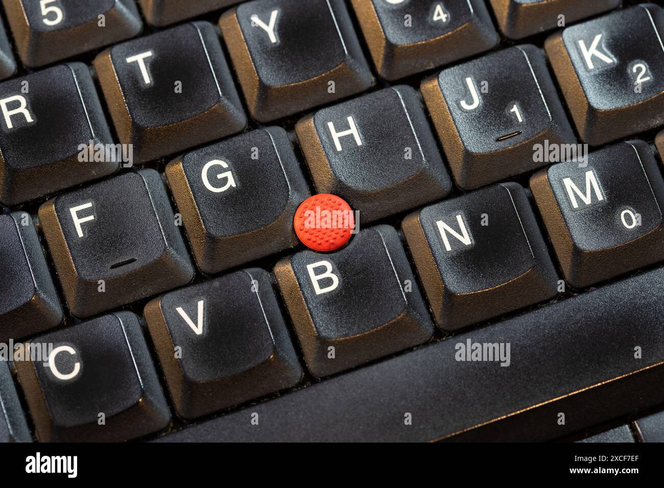 Red pointing stick on a laptop computer keyboard, macro detail extreme ...