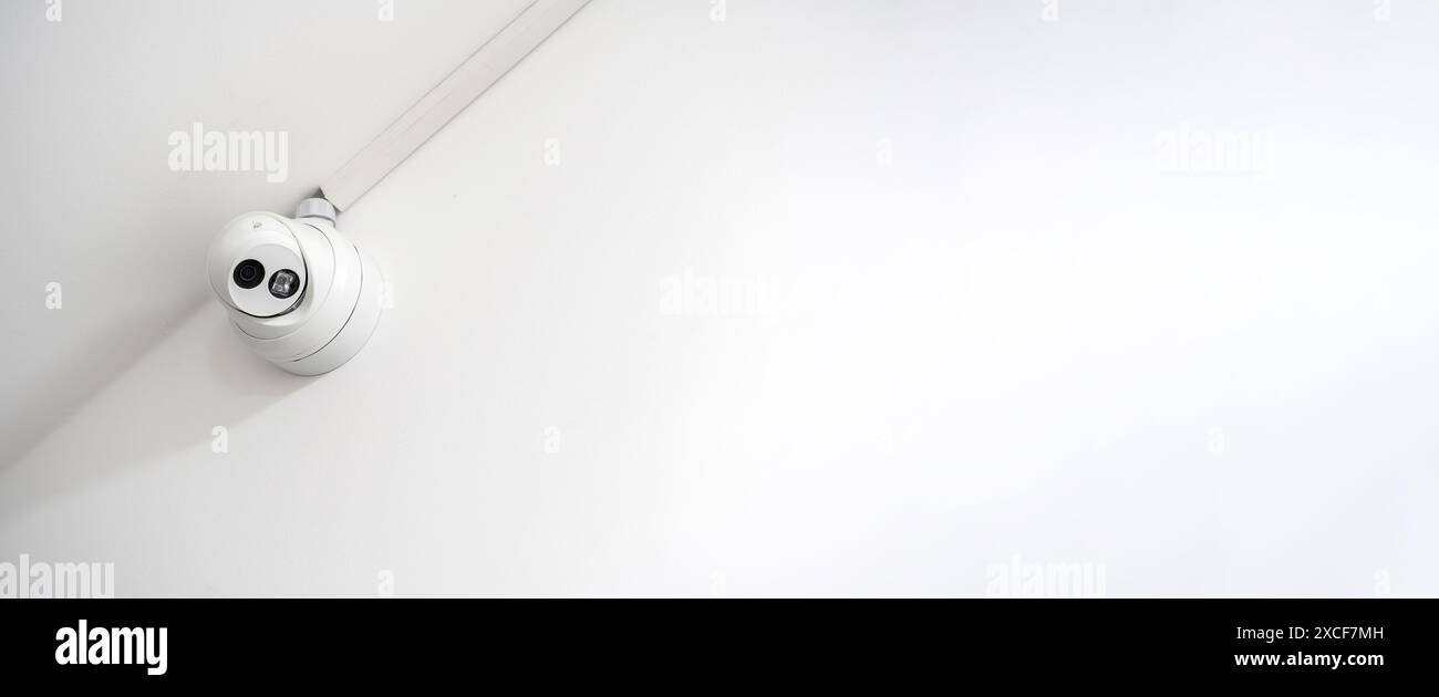 One single simple security camera on a white wall background wide shot ...