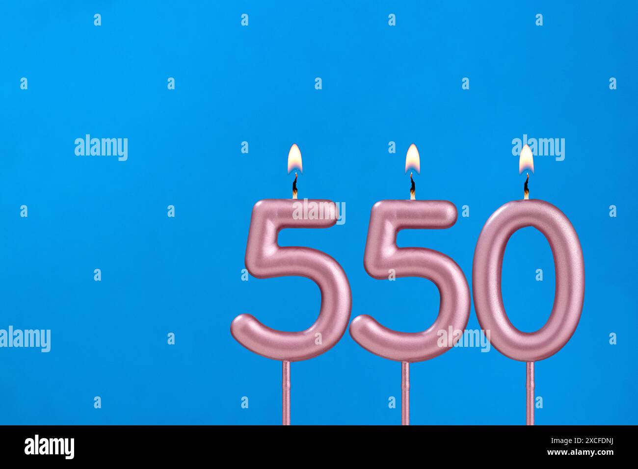 Number 550 - Burning anniversary candle on blue foamy background Stock ...