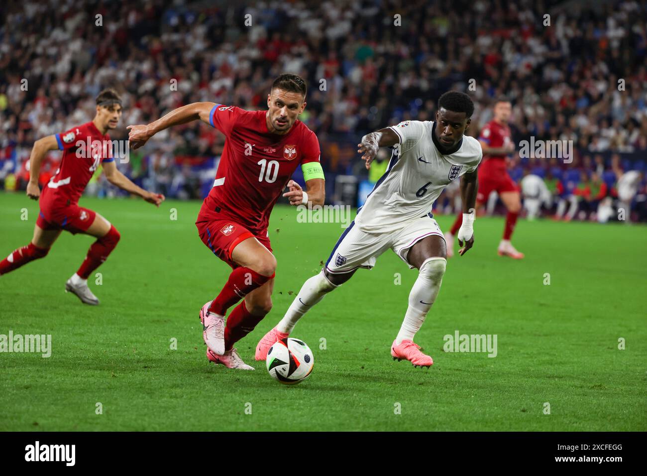 Gelsenkirchen. 16th June, 2024. Dusan Tadic (L) of Serbia vies with Marc Guehi of England during ...