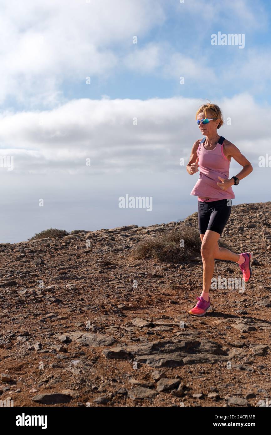 Female runner, dressed in pink and black athletic wear, strides ...