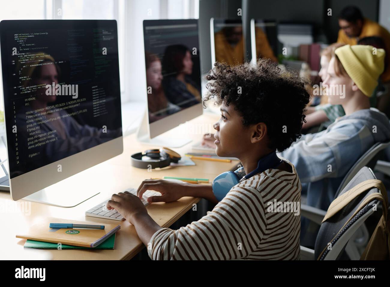 Side view shot of African American teen boy coding on computer during ...