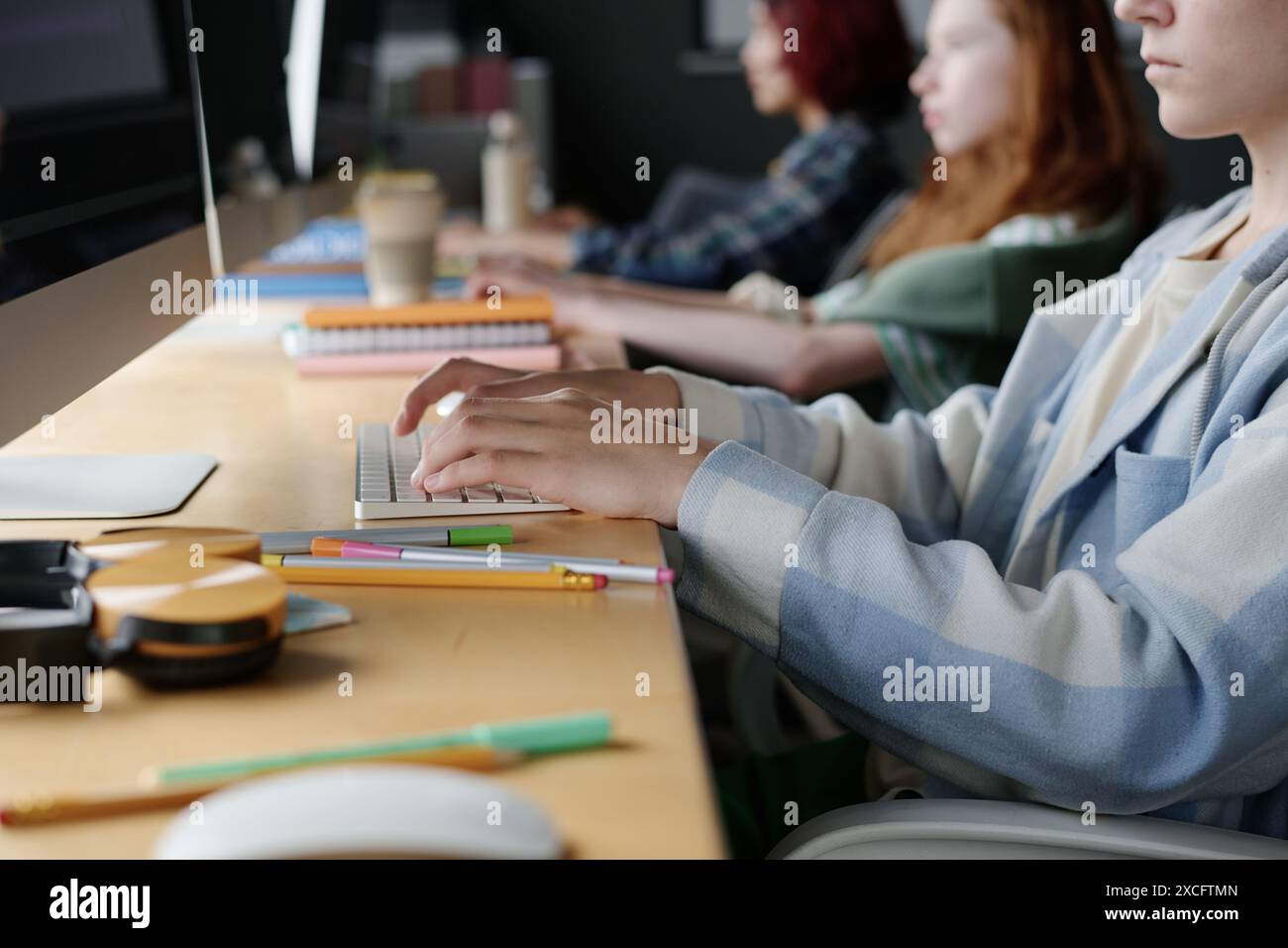 Medium closeup crop shot of hands of teen student typing on computer in ...
