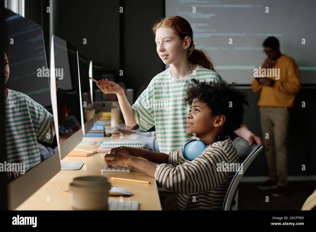 Caucasian teen girl helping her African American male classmate during ...