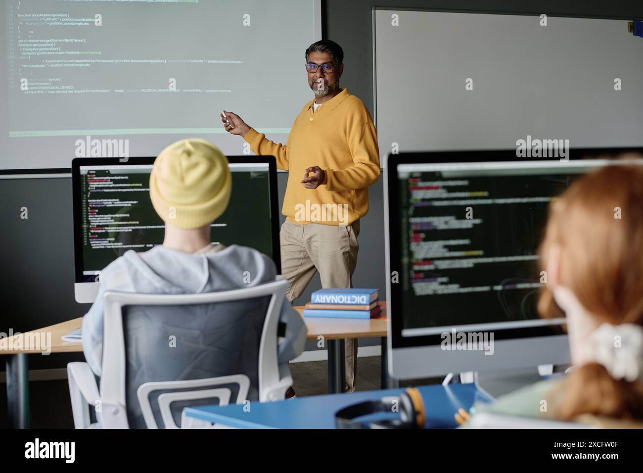 Mature biracial man wearing smart casual clothes teaching coding in ...