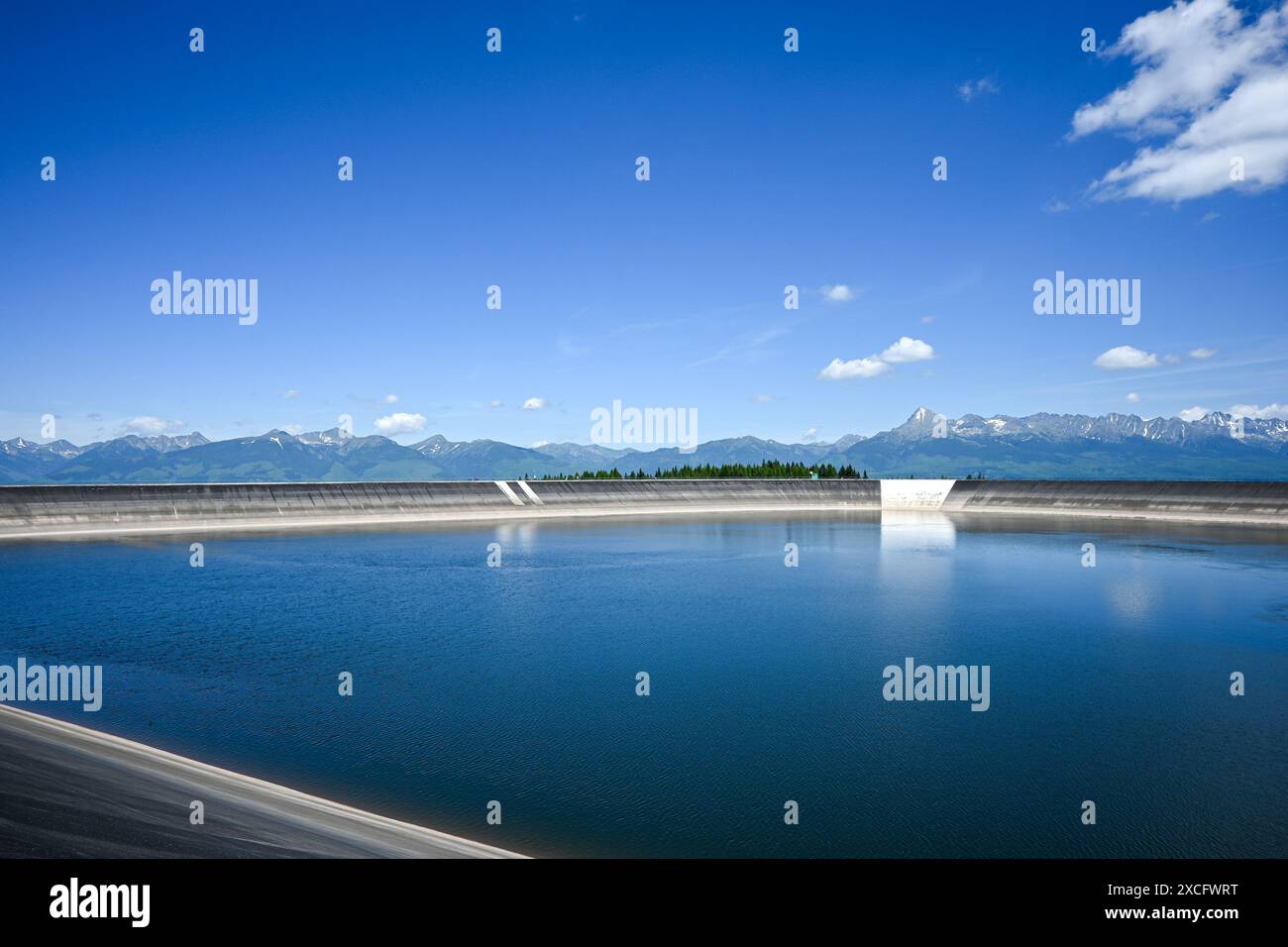 Water reservoir dam holding back water with mountains in background ...