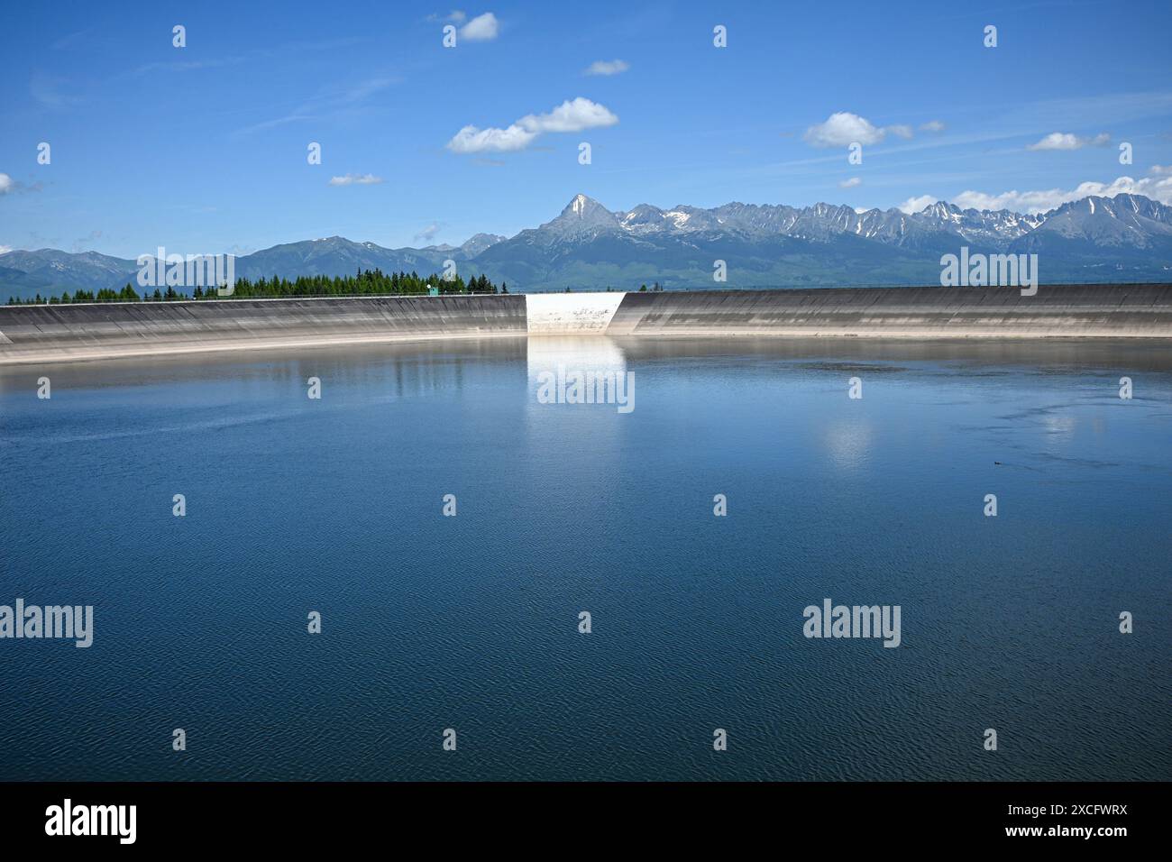 Water reservoir dam holding back water with mountains in background ...
