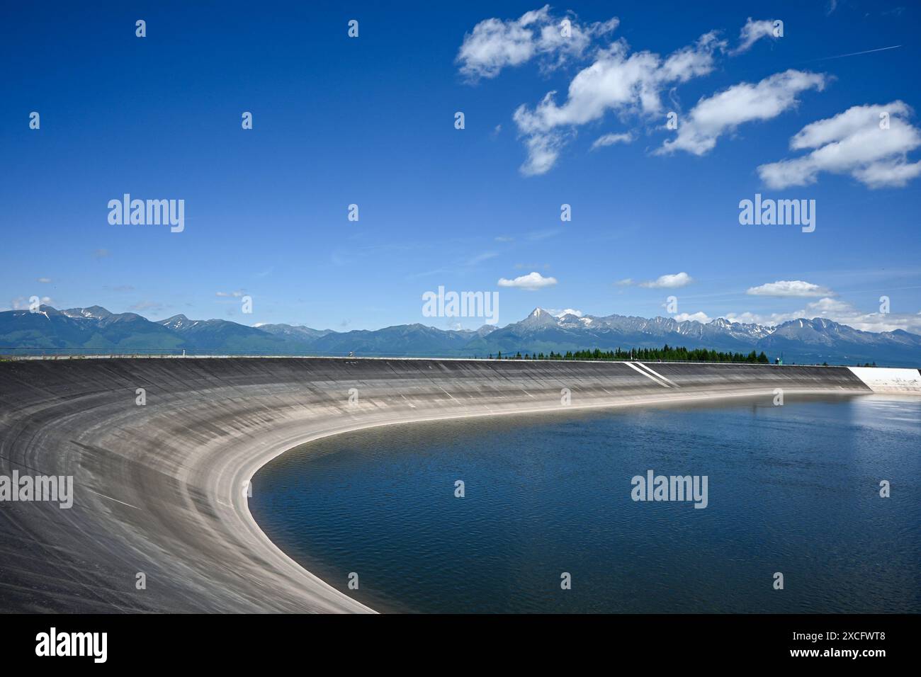 Water reservoir dam holding back water with mountains in background ...