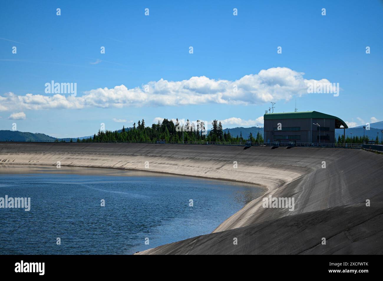 Water reservoir with dam wall and building on a sunny day with blue sky ...