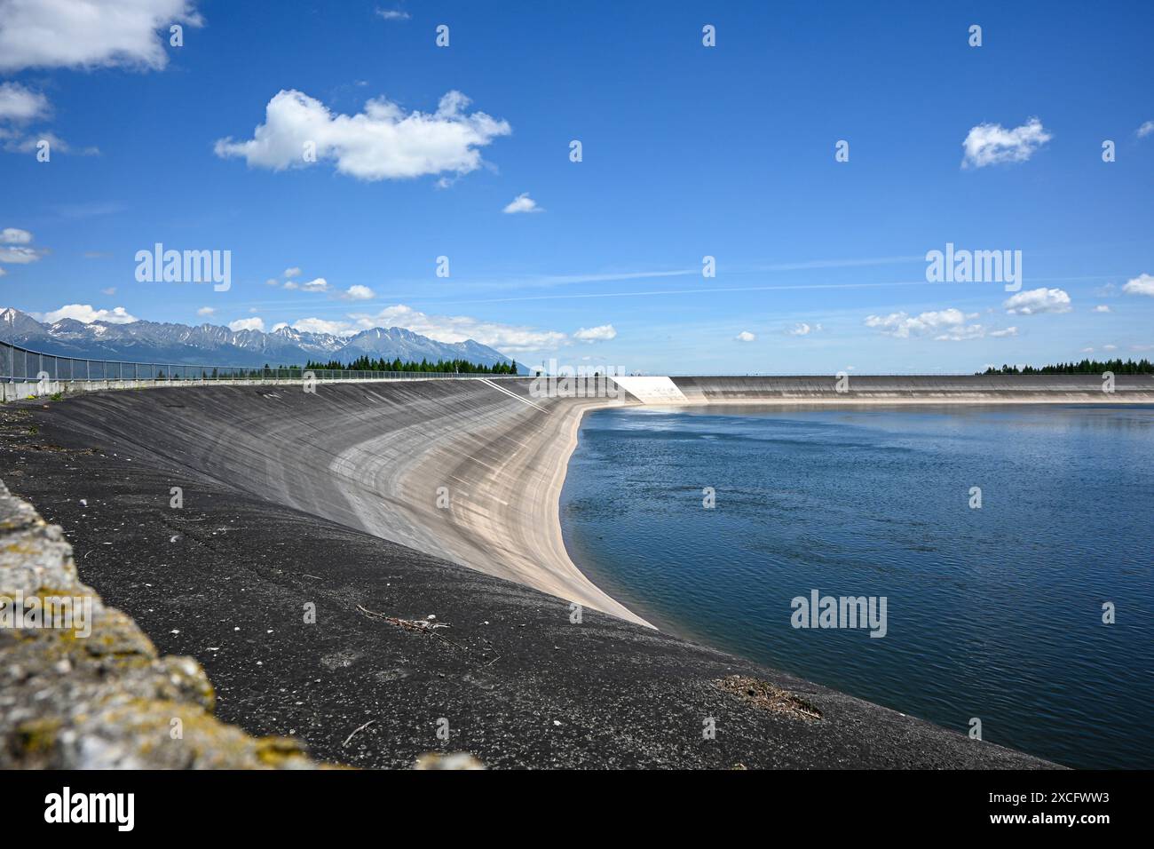Water reservoir dam holding back water with mountains in background ...