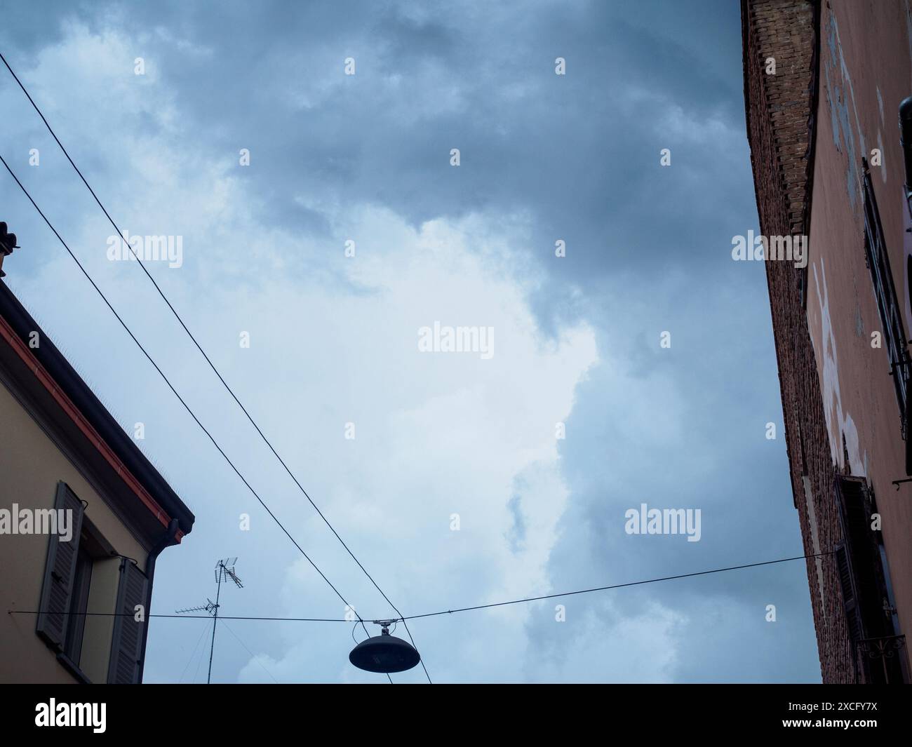 Street light is hanging on wires between residential buildings under a ...