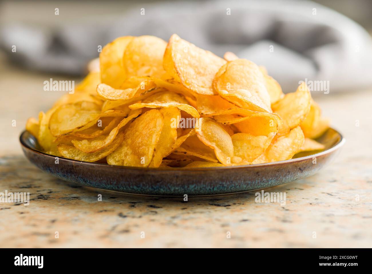 Crispy Potato Chips on plate on a kitchen table Stock Photo - Alamy