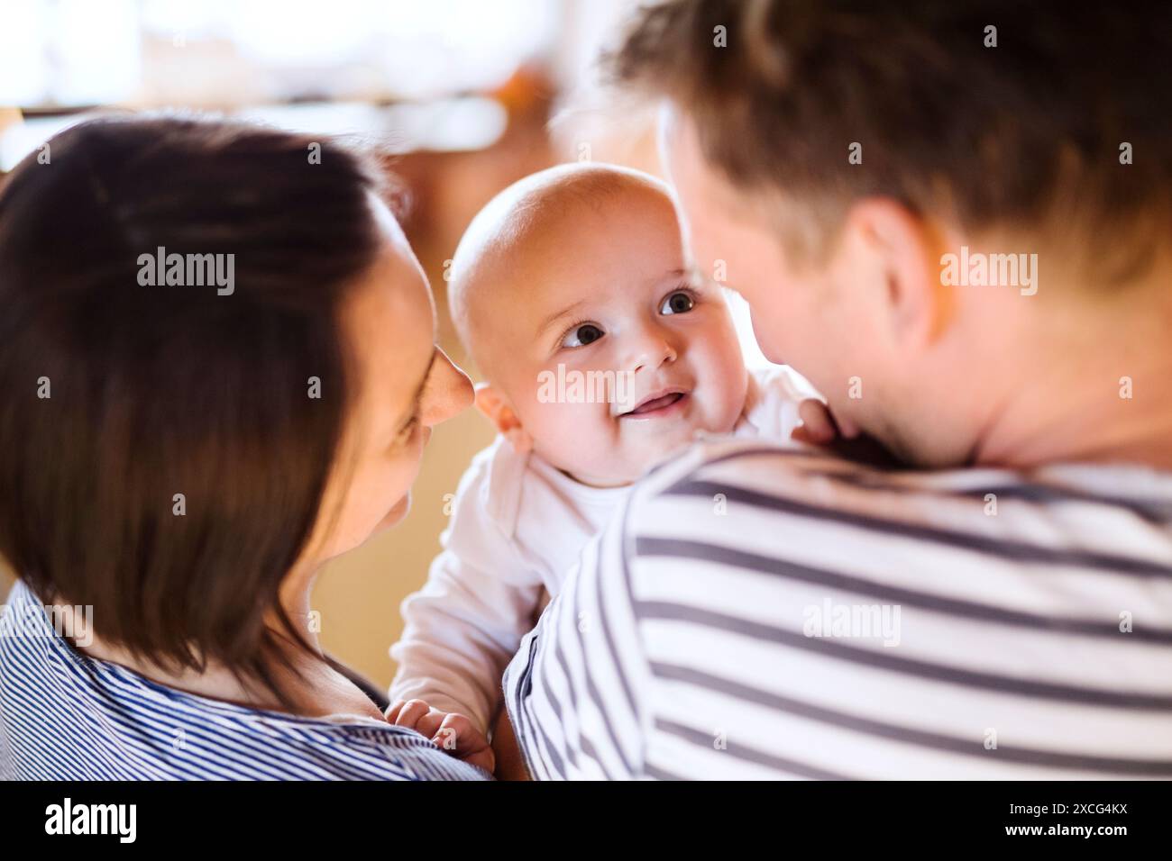 Happy parents holding and playing, kissing small baby, carrying him ...